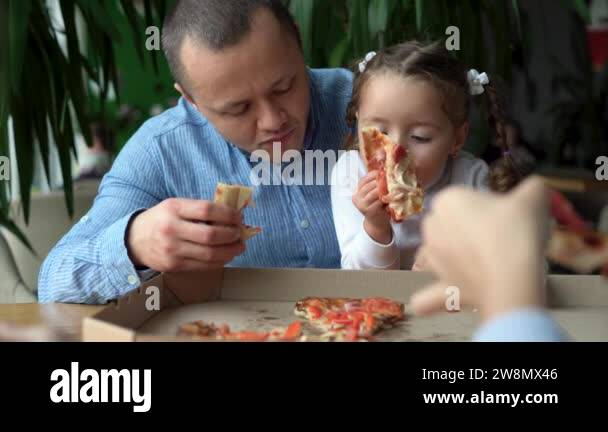 dad and little daughter are eating Italian pizza in a cafe, family in a ...
