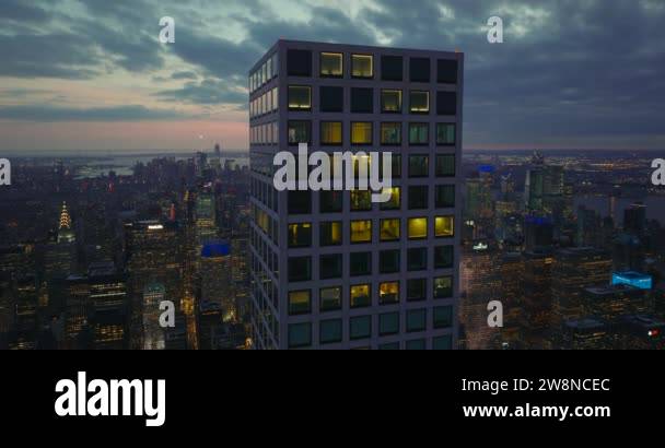 Fly around top of office skyscraper at dusk. Downtown high rise ...