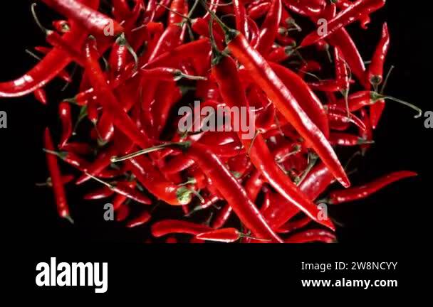 Super slow motion of flying red hot chilli peppers isolated on black ...