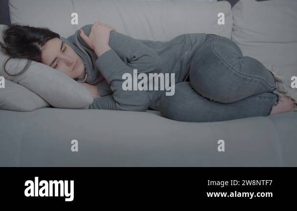 Portrait of a teenage girl lying motionless on a sofa and hugging ...