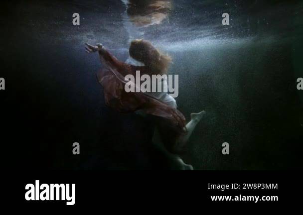 beautiful lady is floating gracefully under water surface of swimming ...