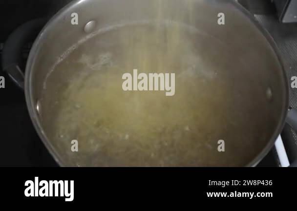 pasta falling into boiling hot water in a saucepan, steam rises from ...