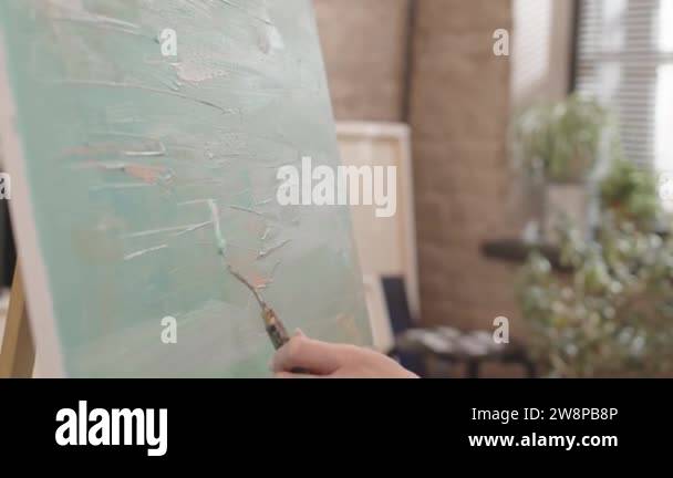 Locked-down of unrecognizable artist with hand only in frame painting ...