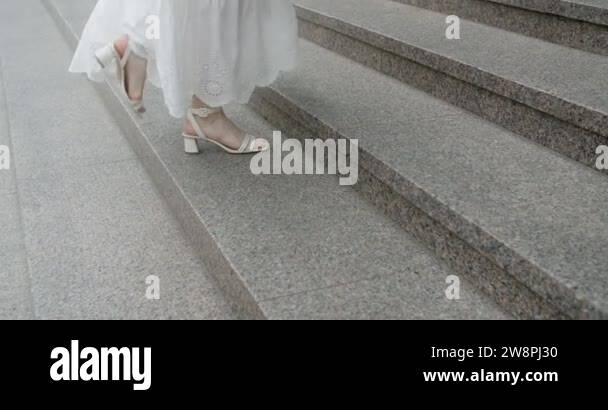 FOLLOWING CAMERA: the legs of dancer woman in white dress walking the ...