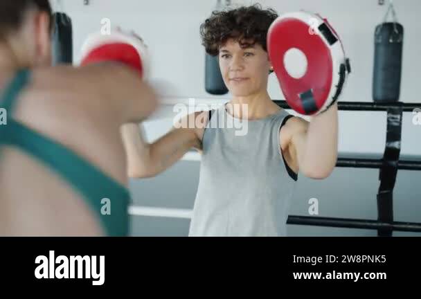 Female boxing coach motivating student young woman training punches ...