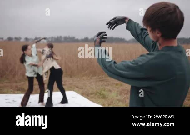 A young guy and two girls demonstrate alternative dances with black ...