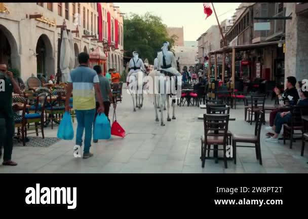 Souq Waqif in Doha, Qatar main street zooming in shot showing Traditional policemen riding ...