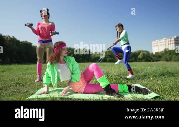 Self confident retro sportswoman lying on exercise mat raising one leg ...