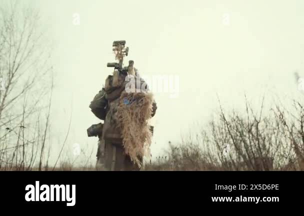 A fully-equipped female sniper navigates the rough terrain, her rifle ...