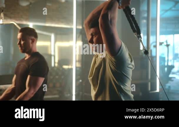 Two focused men engage in an intense crossover workout, simultaneously ...