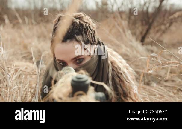 A sniper woman is seen peering through the optical scope of her rifle ...