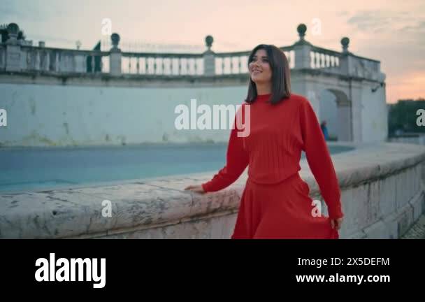 Confident beautiful model walking old city square wearing red dress ...