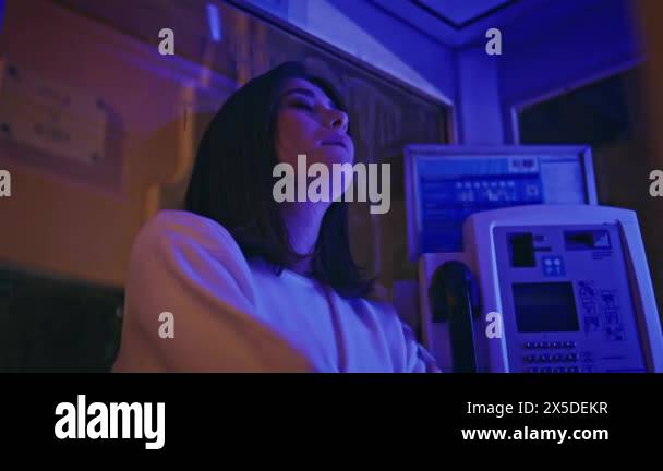 Neon girl thinking phone booth feeling lonely at night closeup. Upset ...