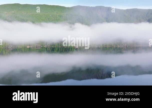 This serene aerial view showcases a layer of morning mist hovering ...