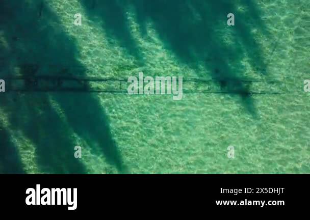 Shadows of a submerged rail track dance across the textured sandy ...