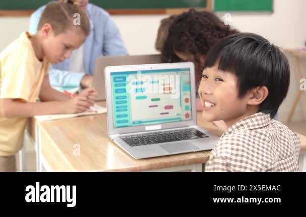 Energetic asian boy coding program and looking at camera in STEM class ...