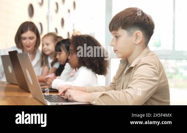 Boy playing laptop with multicultural friend learning prompt at STEM technology class ...