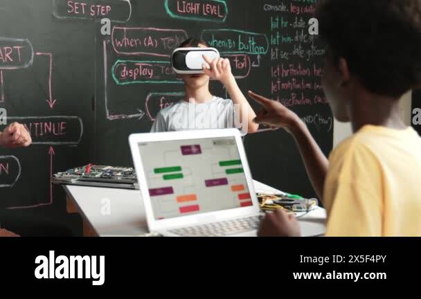 African boy programming system while caucasian girl enter metaverse while sitting at blackboard ...