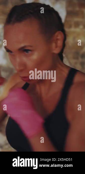 Vertical screen: Athletic woman engages in shadow boxing, her stance ...