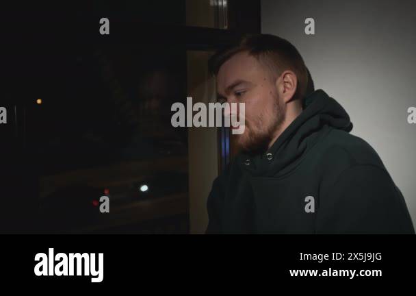 Sad man at night window of house. Media. Man looks out window with sad ...