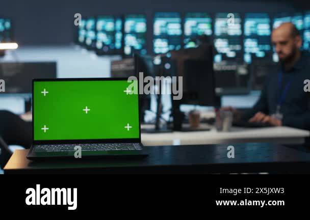 Focus On Isolated Screen Laptop In Data Center With Man In Blurry Background Coding Managing