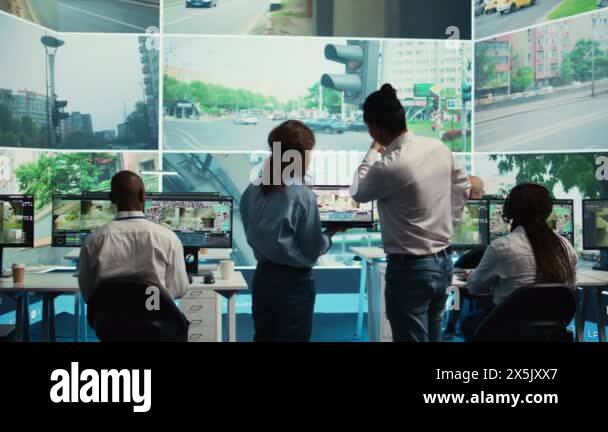 Diverse team following city traffic on a display in monitoring room ...