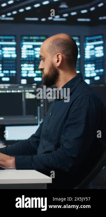 Vertical video Man programming in high tech facility with server rows providing computing ...