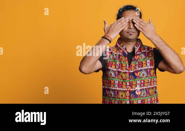 Man wearing traditional indian clothing covering eyes, ears and mouth ...