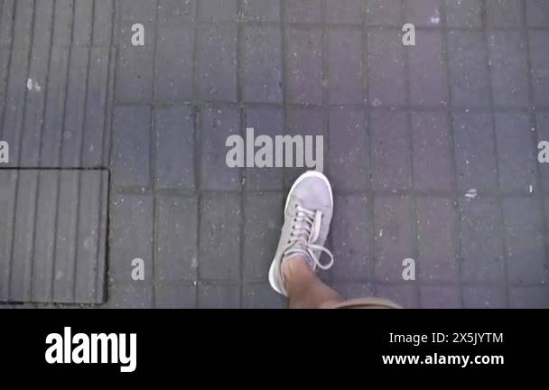Man in jeans and white sneakers walking on paving slabs, top view ...