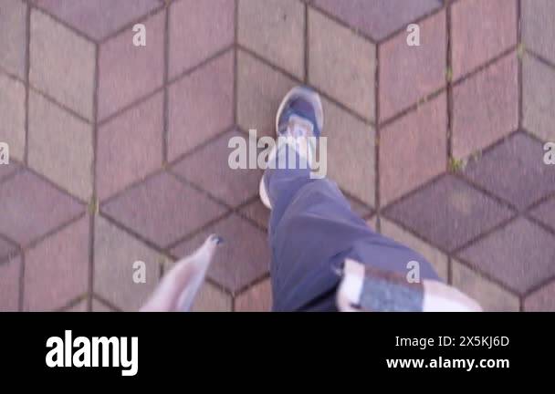 Man in jeans and white sneakers walking on paving slabs, top view ...