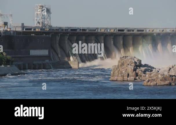 A waterfall cascades down a dam into a body of water, creating a ...