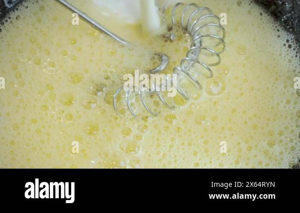 Preparation of pancake batter. Adding milk to beaten egg with sugar to ...