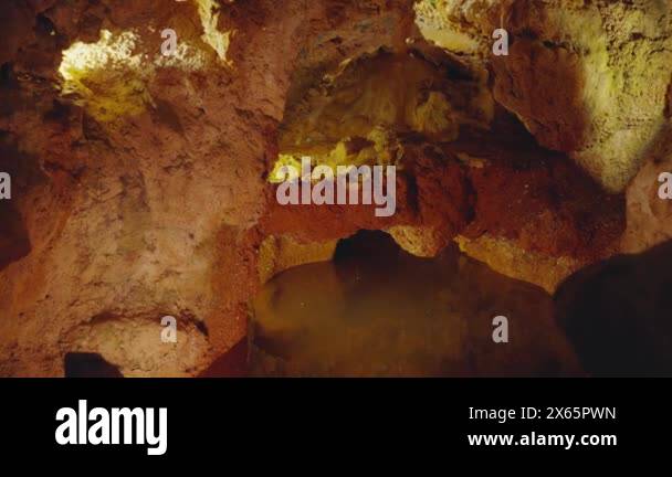 Explore the mystique of a dimly lit underground cave with natural water ...