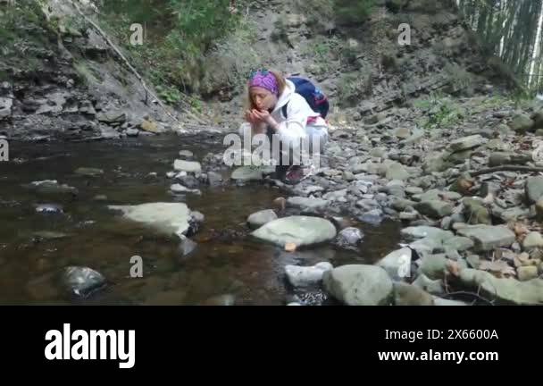 Tourist drinks from river. Close-up of girl traveler drinking water ...