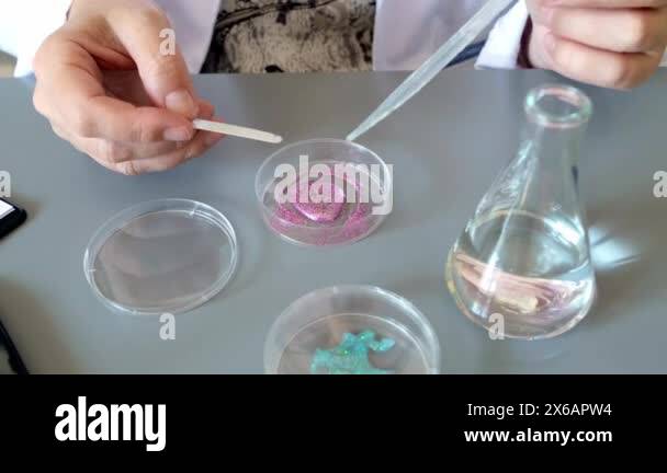 Unrecognizable female scientist pouring liquid from pipette over pink ...