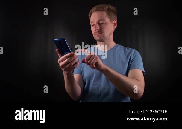 a stylish young man intently engages with a mobile device on a minimal ...