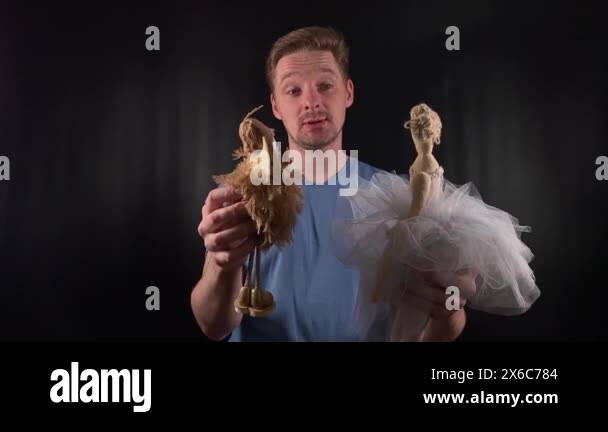A portrait of a handsome young white man holding puppets, playing with ...