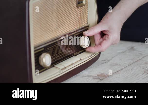 A close-up view of a womans hand tuning the knobs on an old-fashioned ...