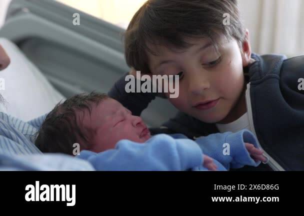 Young boy watching his newborn baby brother at hospital after birth ...