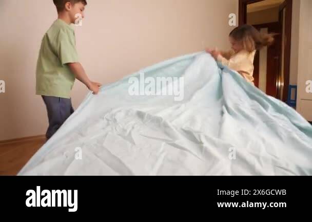 a boy and a little girl learn to make their own bed. Children change ...