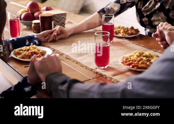 Happy family holding hands and praying with closed eyes before having a ...