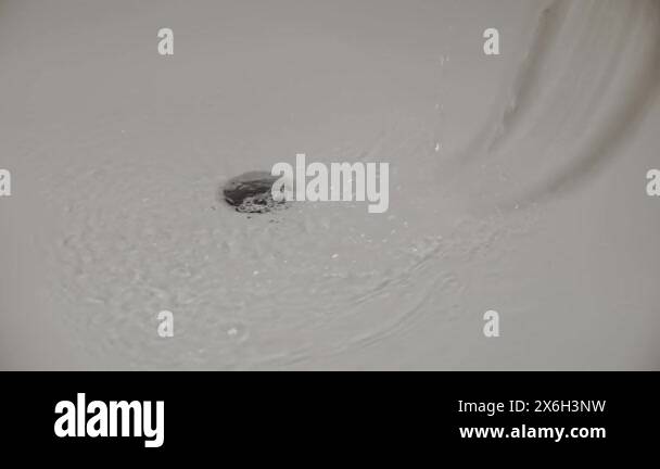 Close-up of water pouring into a white sink in a bathroom, showcasing ...