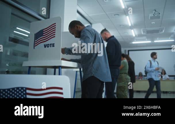 African American man votes in booth in modern polling station office ...