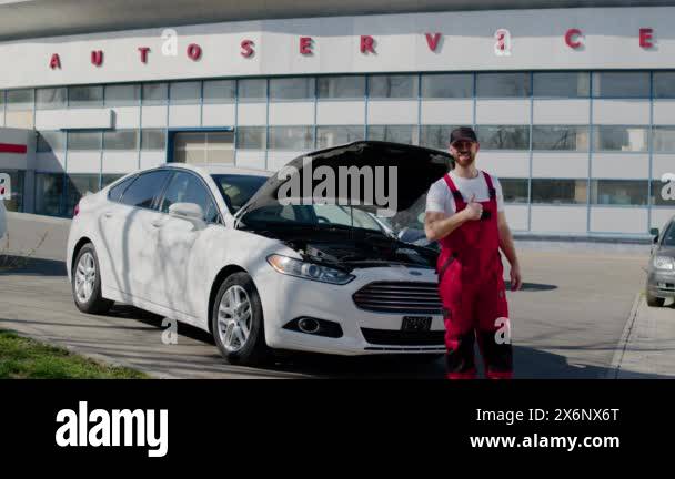 Automotive technician stands proudly beside recently repaired car job ...