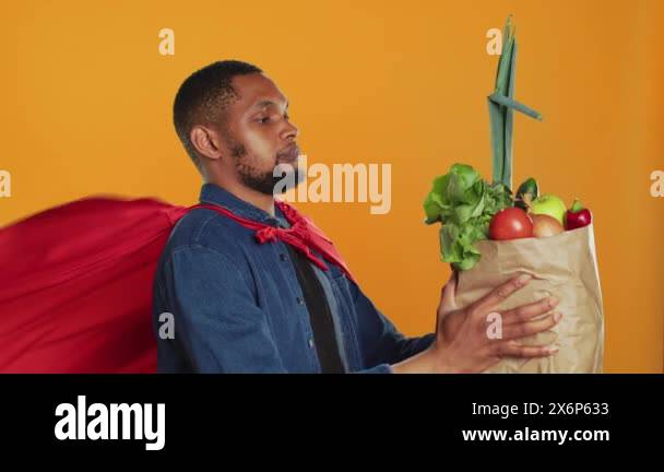 African american guy posing as a superhero with fresh ripe produce ...