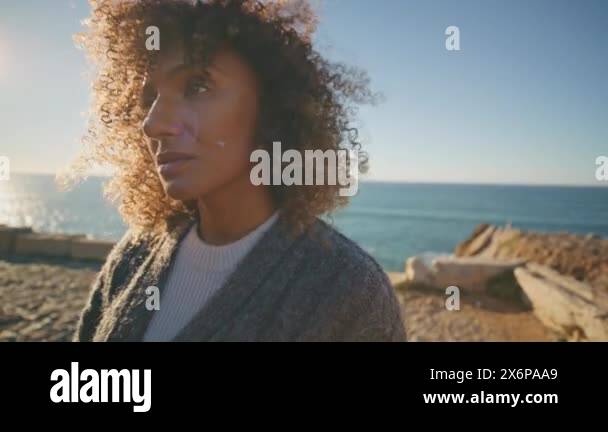 Closeup upset girl looking distance at sea beach. Portrait sad woman face with windy curly hair ...