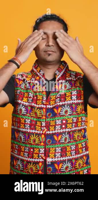 Vertical video Man wearing traditional indian clothing covering eyes ...
