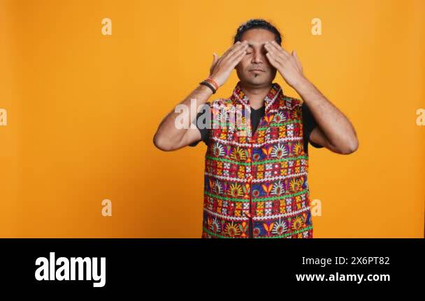 Man wearing traditional indian clothing covering eyes, ears and mouth ...