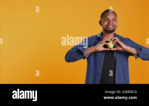 African american relaxed guy does a heart shape sign with an apple ...