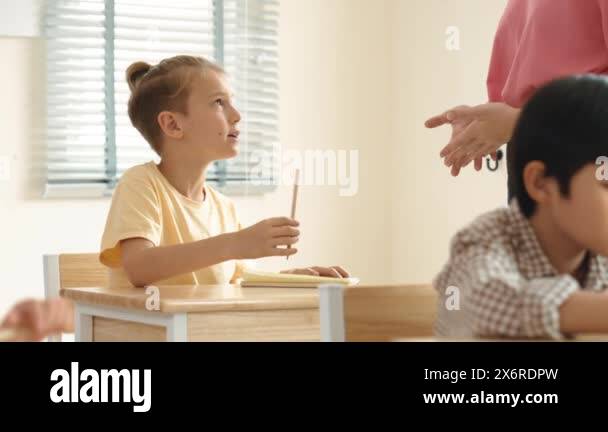 Beautiful teacher explaining test while caucasian boy doing classwork ...